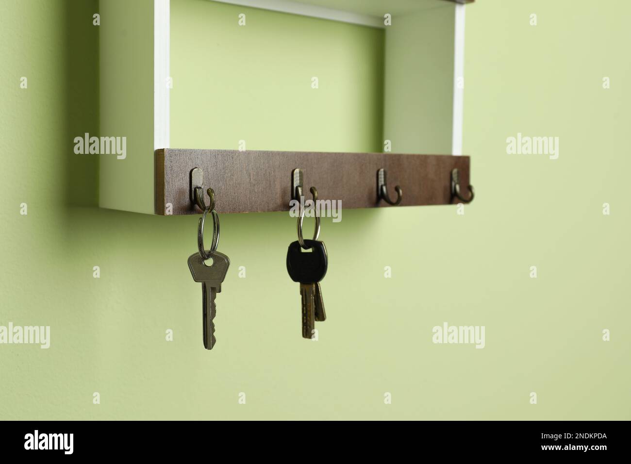 Wooden hanger for keys on light green wall Stock Photo - Alamy