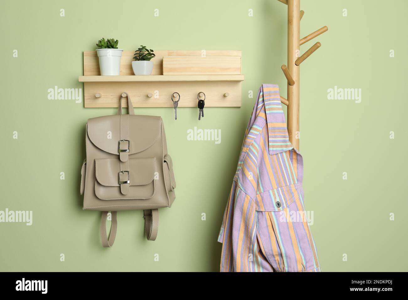 Wooden hanger for keys on light green wall Stock Photo - Alamy