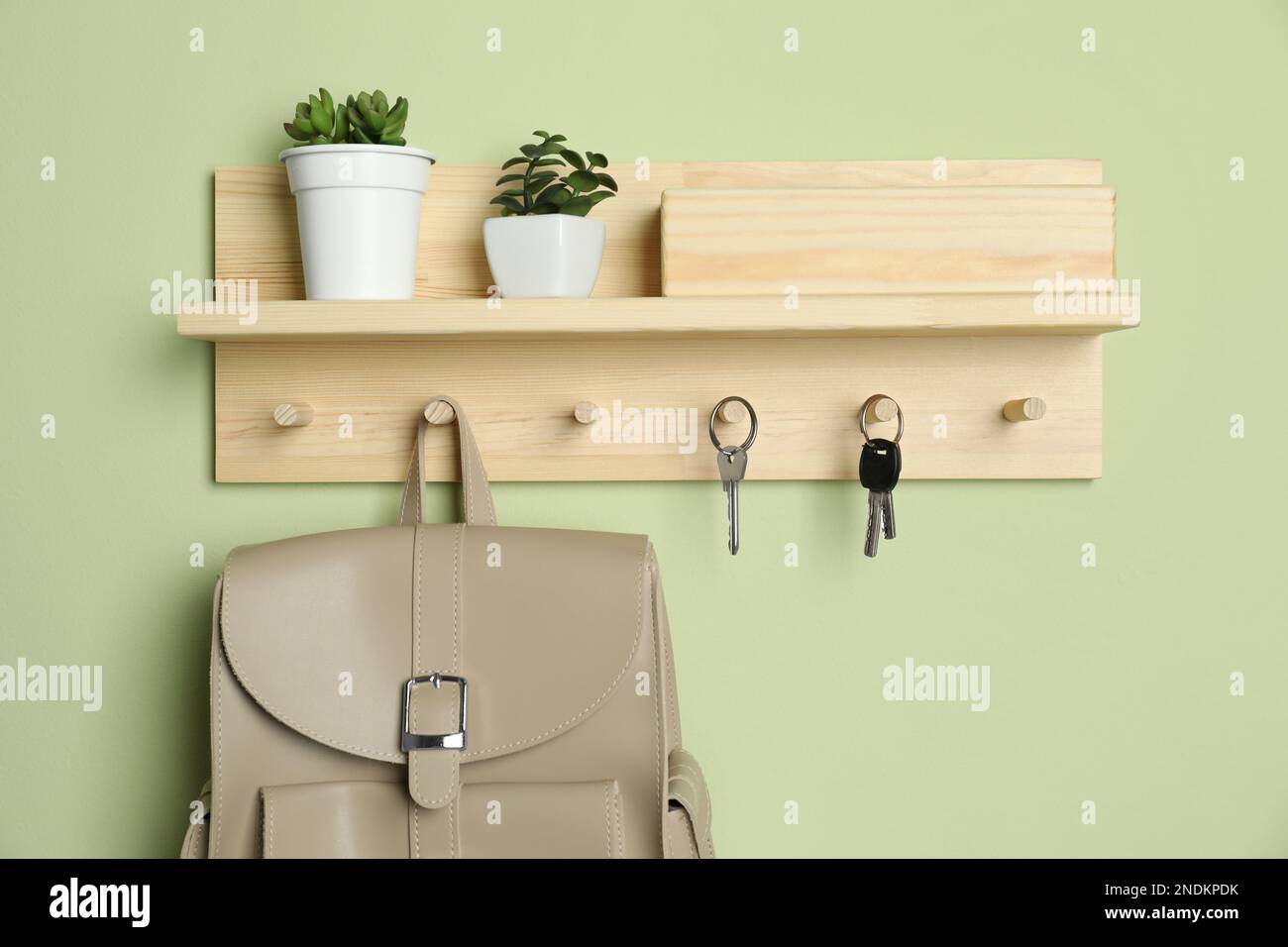 Wooden hanger for keys on light green wall Stock Photo - Alamy