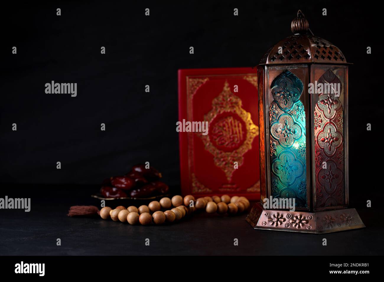 Composition with Arabic lantern and quran on black table. Space for ...