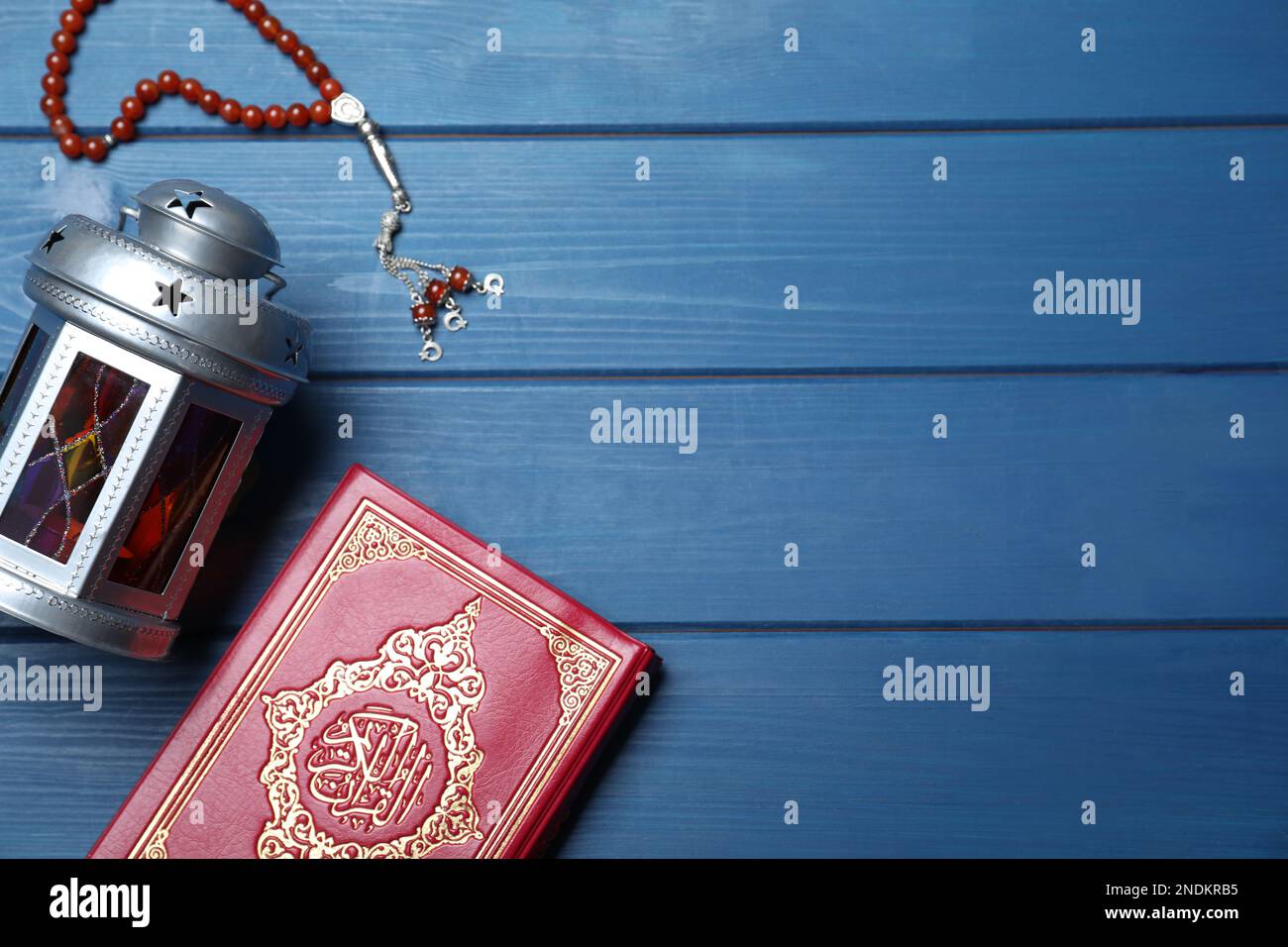 Arabic lantern, quran and misbaha on blue wooden table, flat lay. Space ...