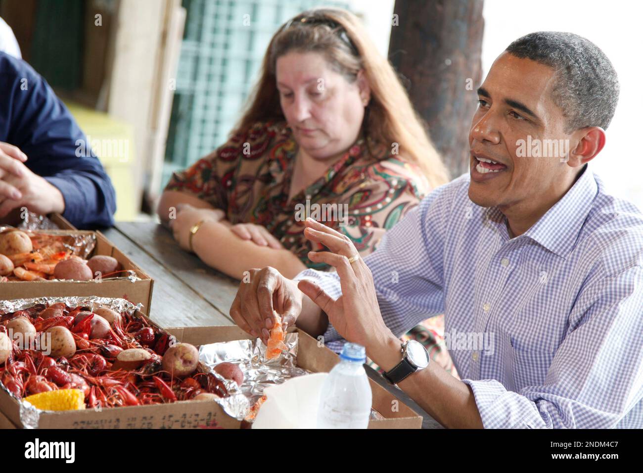 President Barack Obama eats a shrimp as he sits next to convenience ...