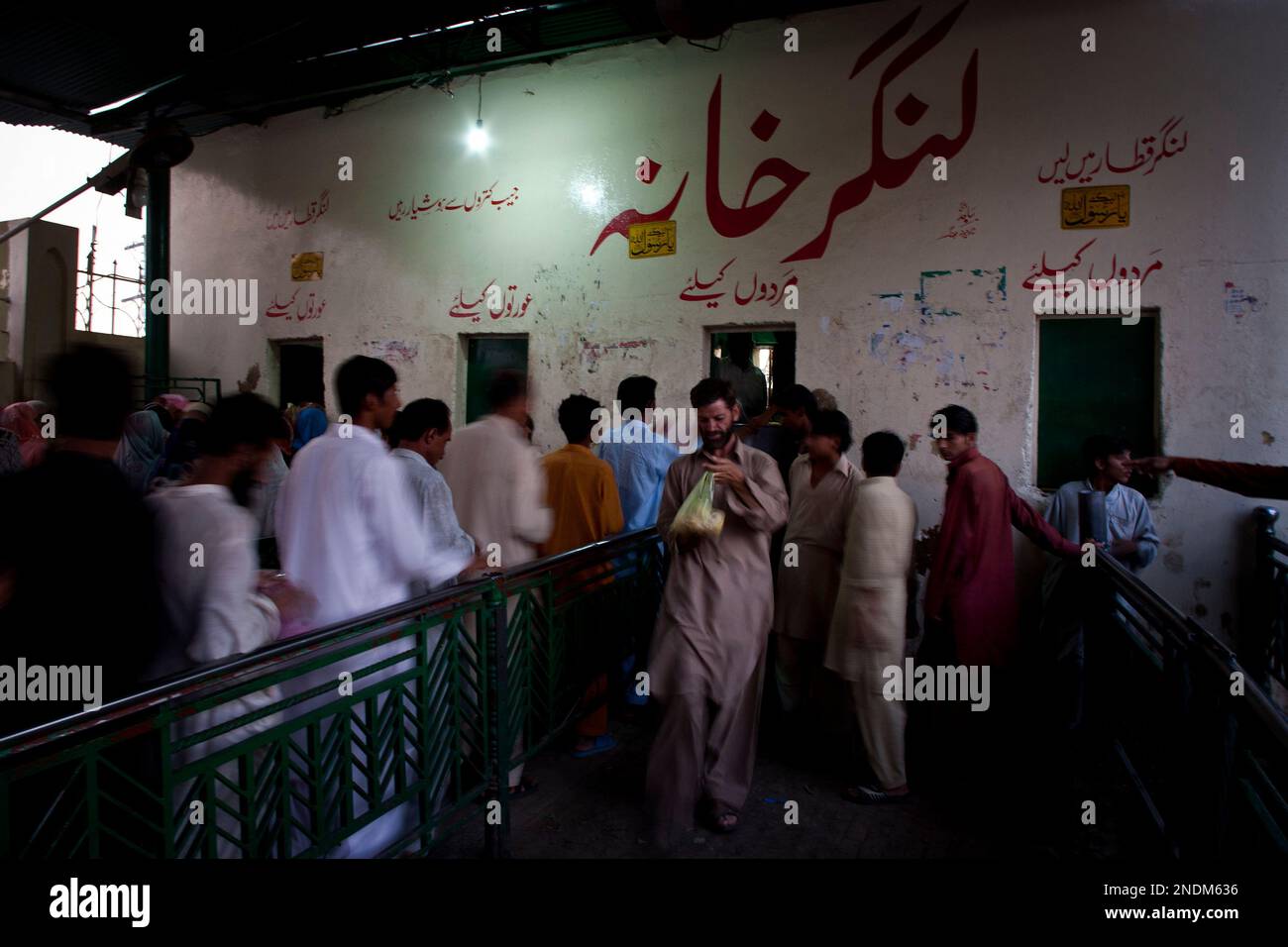 Poor Pakistani people line up to get free food distributed at the Bari ...