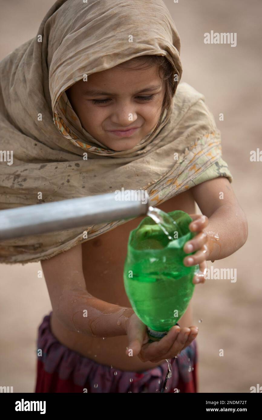 A Pakistani child filling up drinking water from a water host in a poor ...