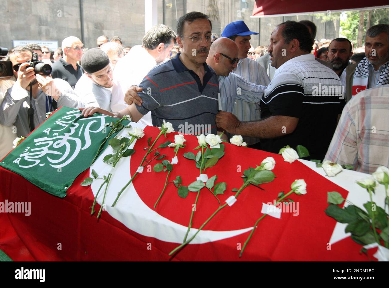 Father Ahmet Dogan, center, touches the flag draped coffin of his son Furkan Dogan, as more than ...
