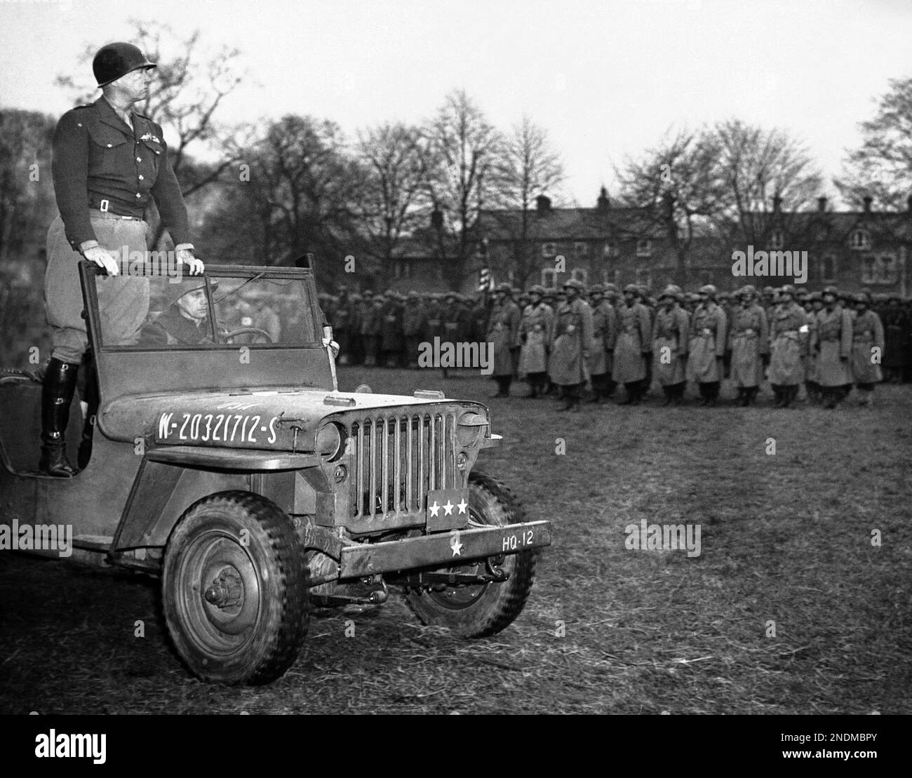 Standing in a jeep, Lieutenant General George S. Patton reviews troops ...
