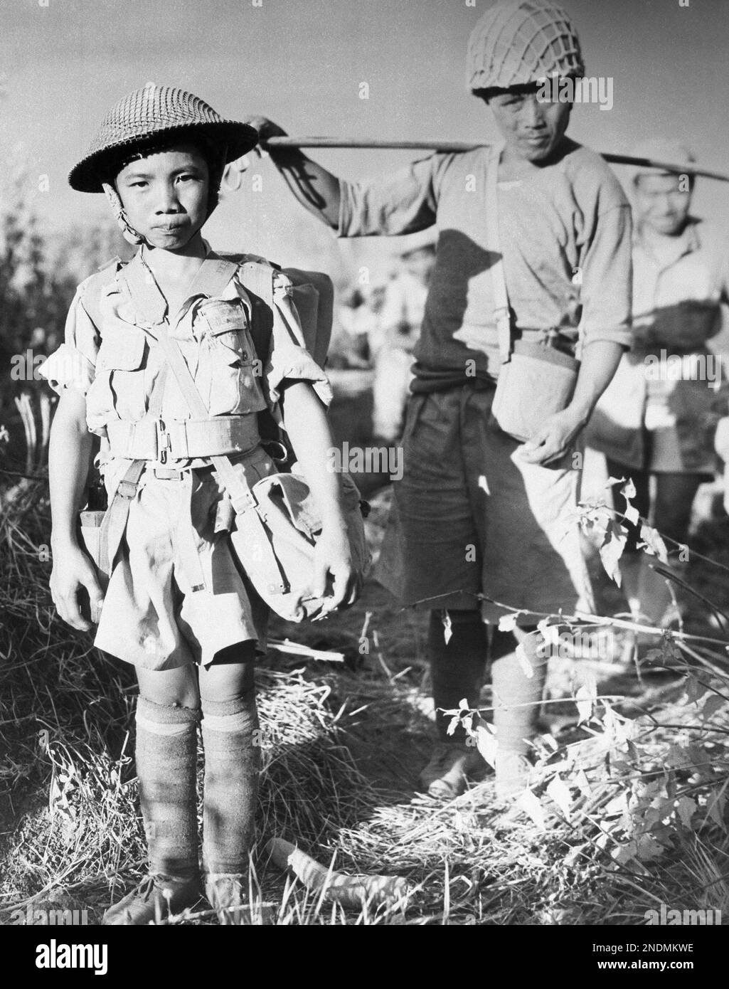 This Chinese soldier, 10 years old, wearing a heavy pack, waits with ...