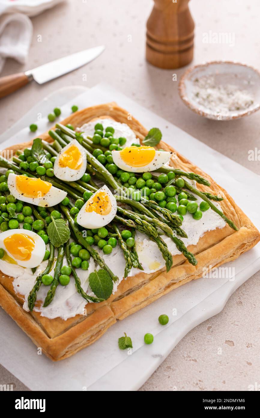 Fresh spring tart with green peas, boiled eggs and asparagus on puff ...