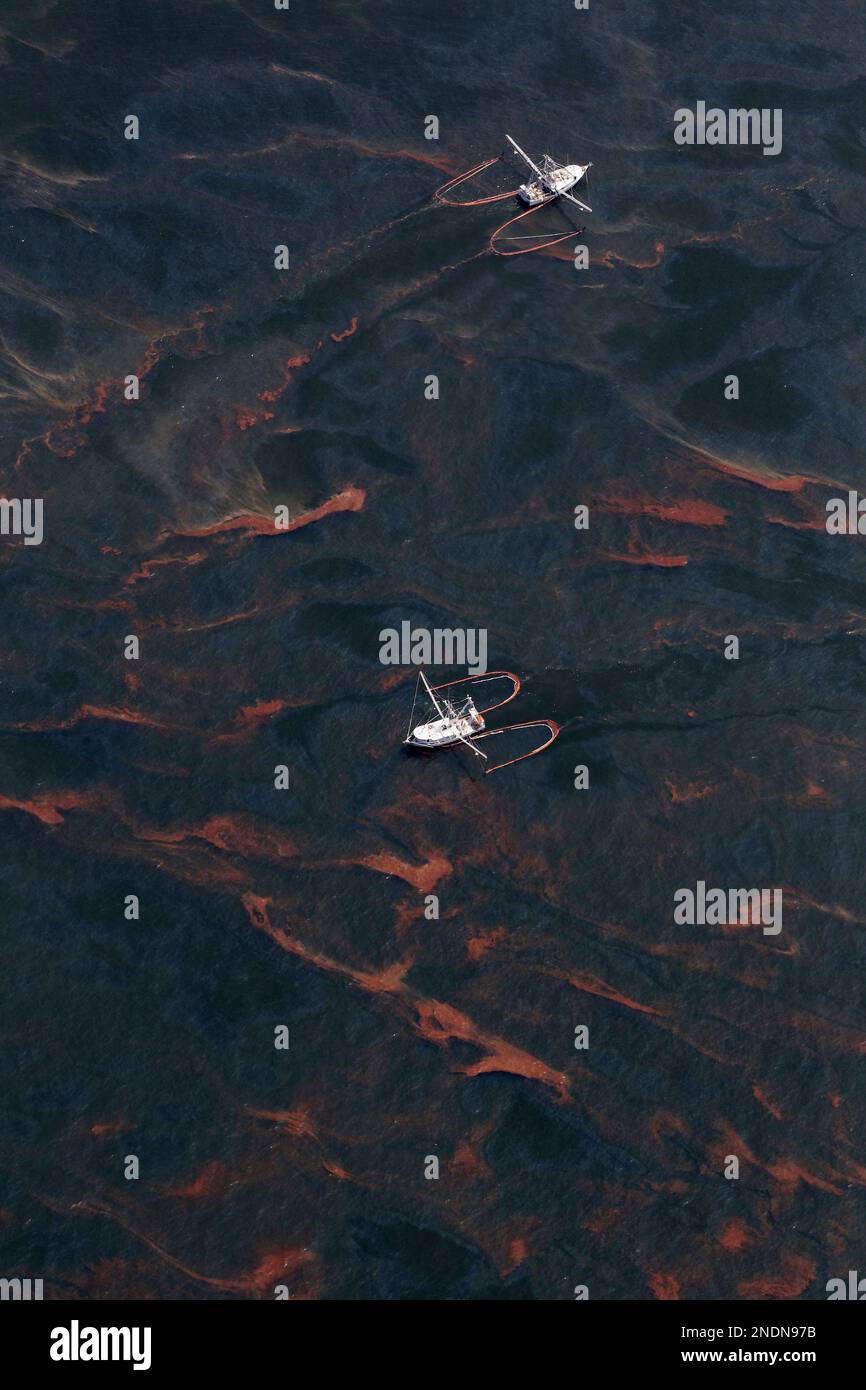 Shrimp boats are used to collect oil with booms in the waters of ...