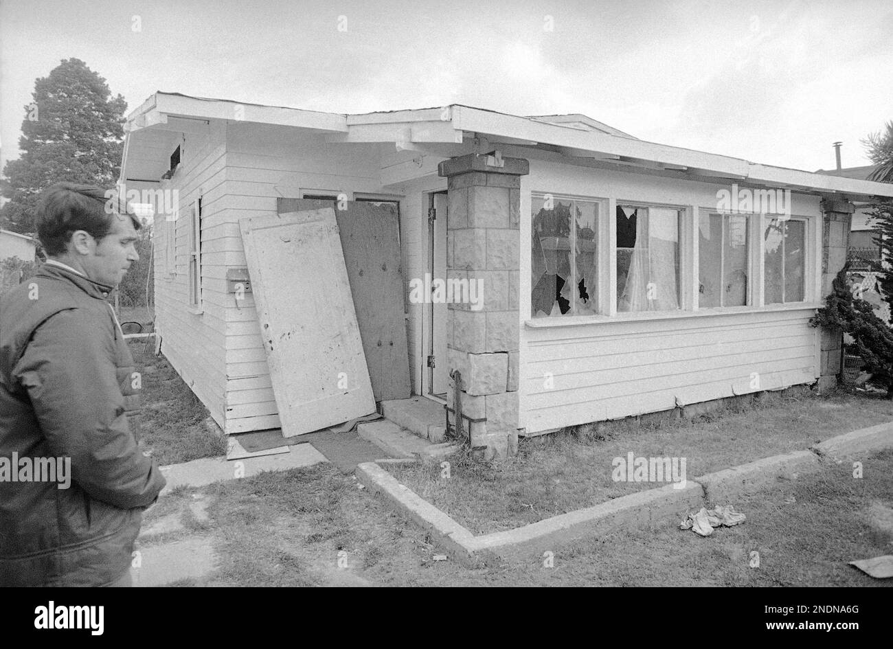 A spectator stands outside a small frame house in south-central Los ...