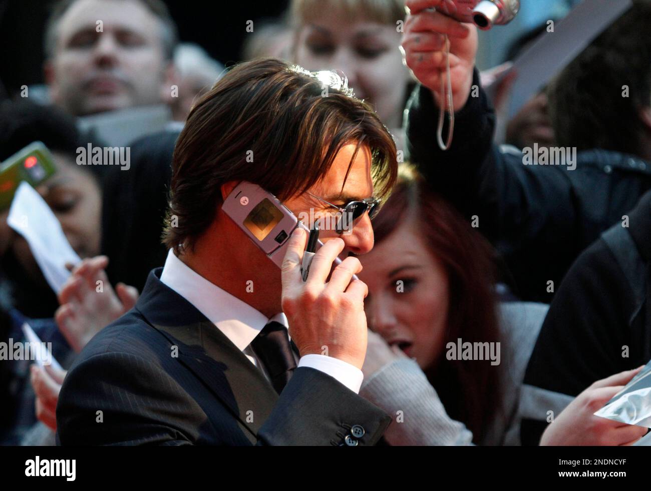 U.S. actor Tom Cruise uses a phone handed to him by a fan to talk to ...
