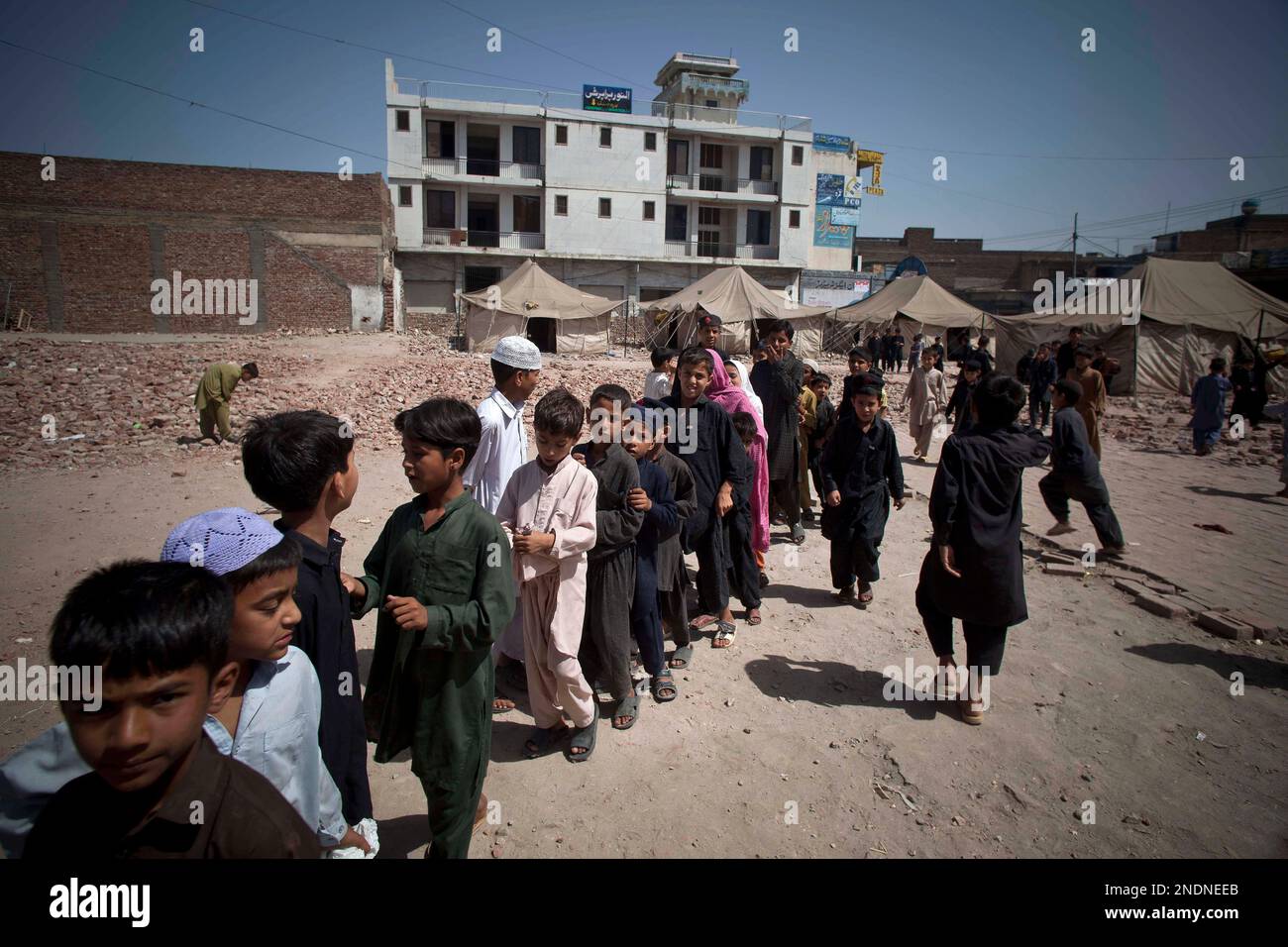 Pakistani students line up outside a tent serving as a makeshift ...