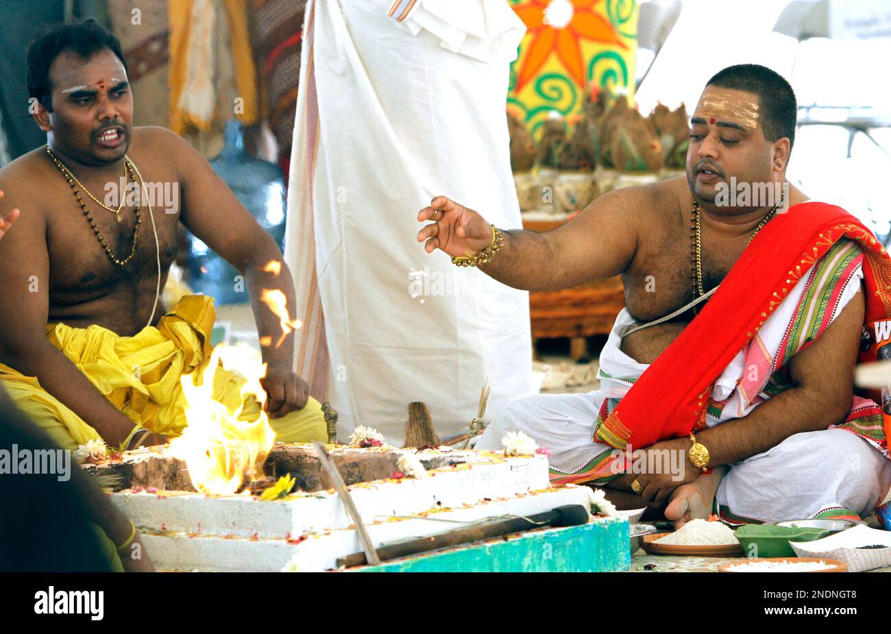 Visiting Hindu priests perform a blessing with rice and flame as part ...