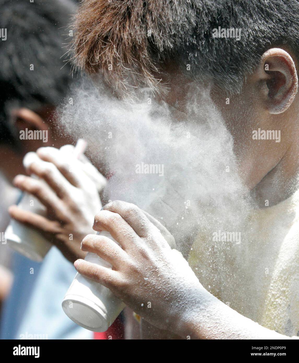 A Filipino boy uses straw to blow out powder inside a plastic cup ...