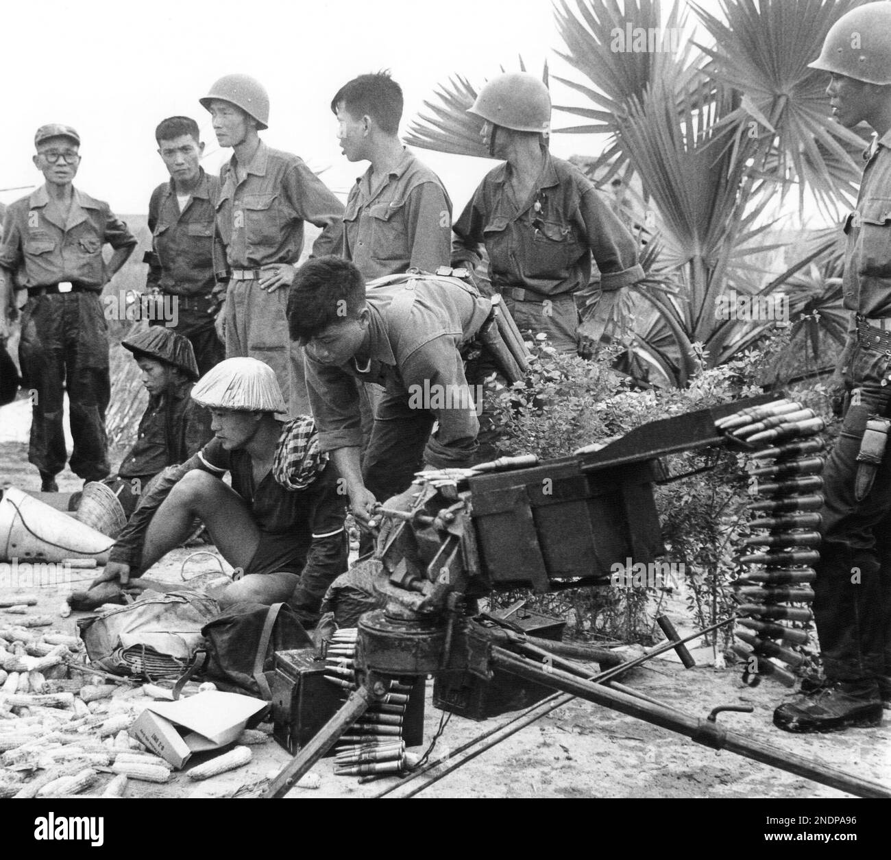 Two Viet Cong guerrillas sit on the ground with captured 50 caliber ...