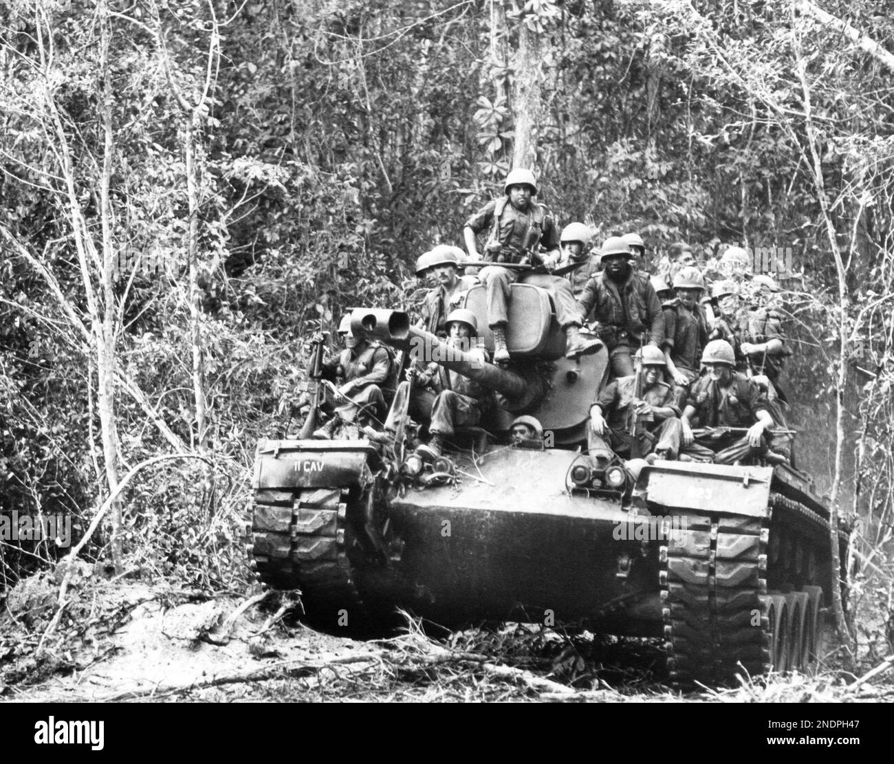 Troops of the U.S. 11th armored cavalry regiment ride tank moving through war zone C in Vietnam ...