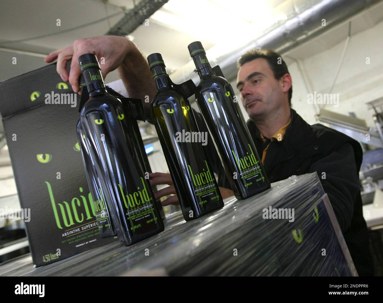 An employee of the Combier distillery shows absinthe bottles for export ...