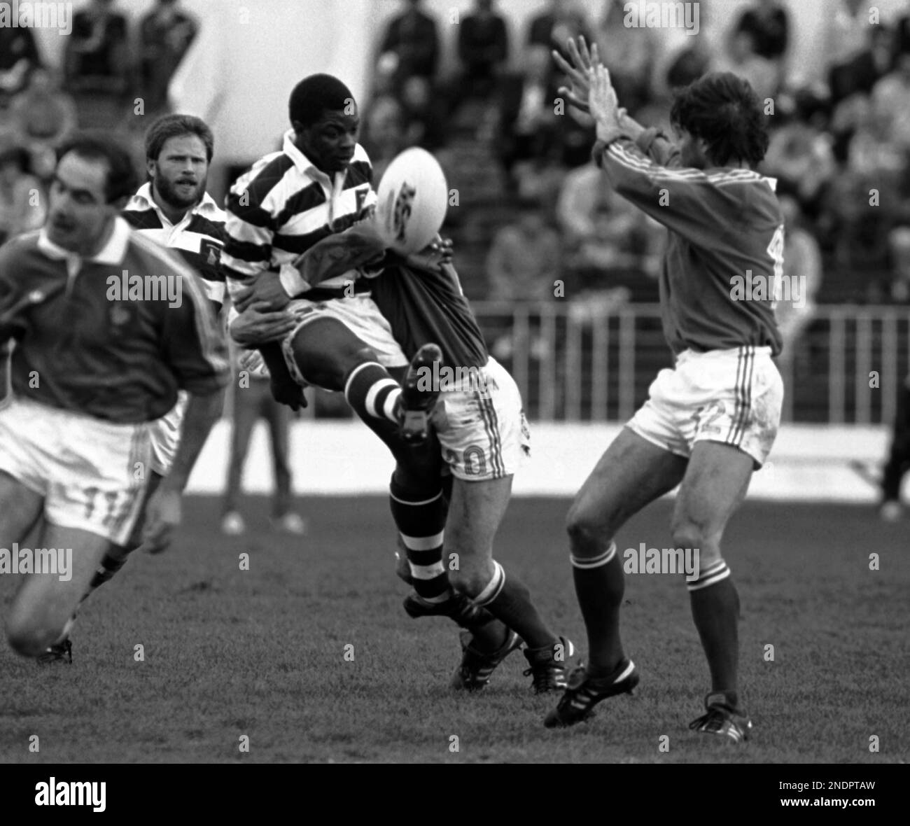 Zimbabwe's Richard Tsimba is tackled heavily by France's Philippe Sella ...
