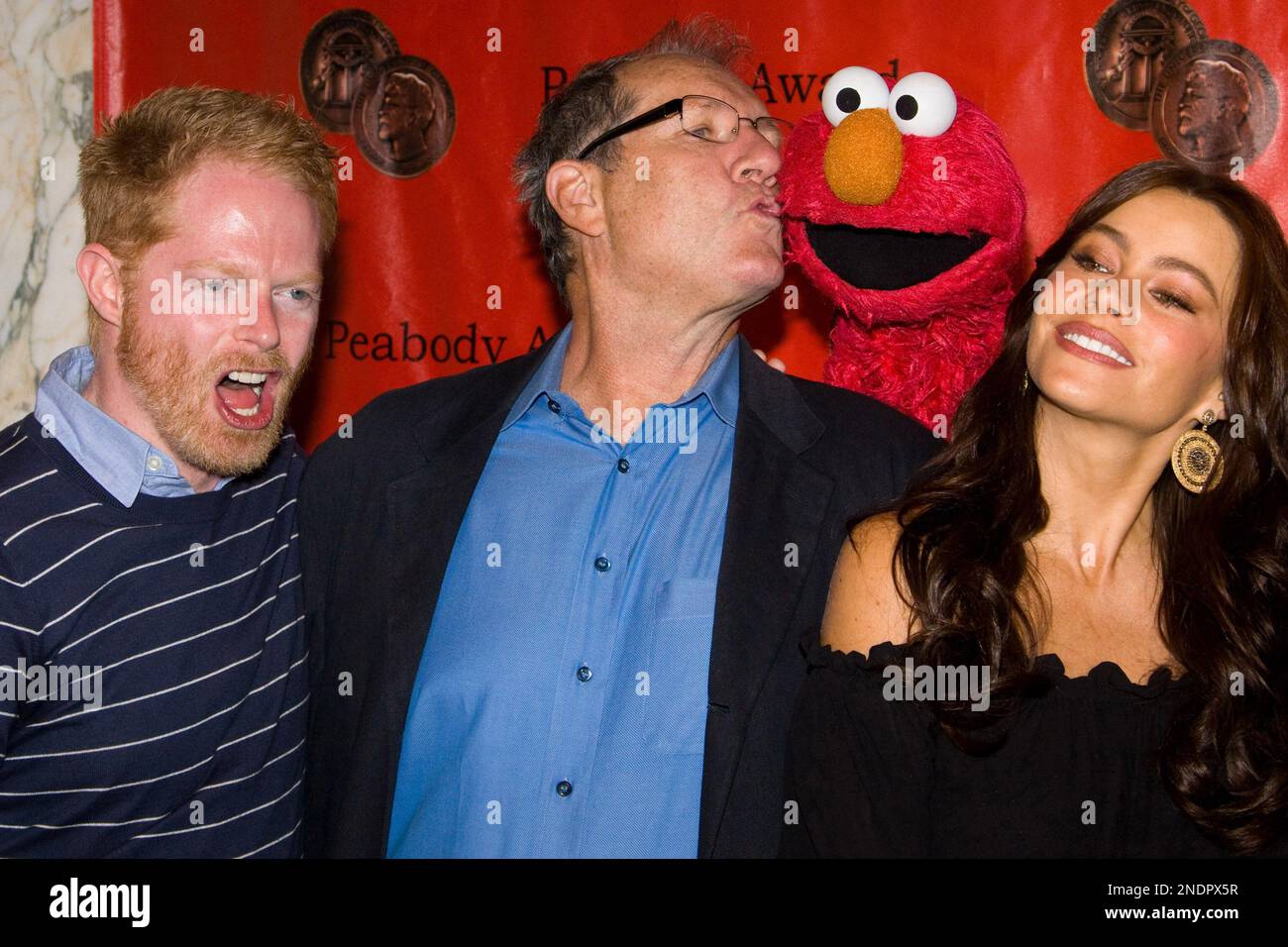 Jesse Tyler Ferguson, left, Ed O'Neill, kissing Sesame Street character ...
