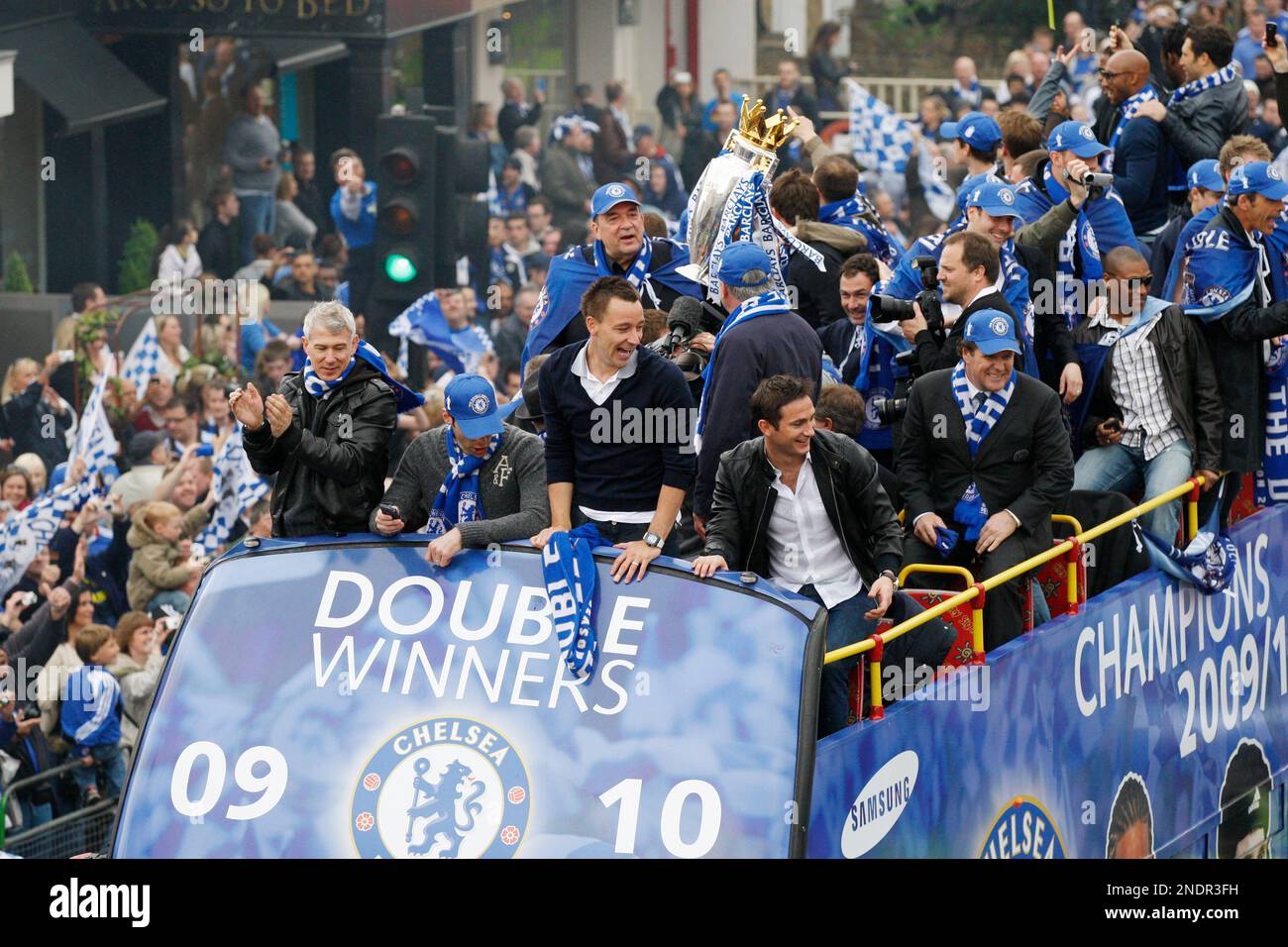 The Chelsea team react from the top of a bus, as fans line the streets ...
