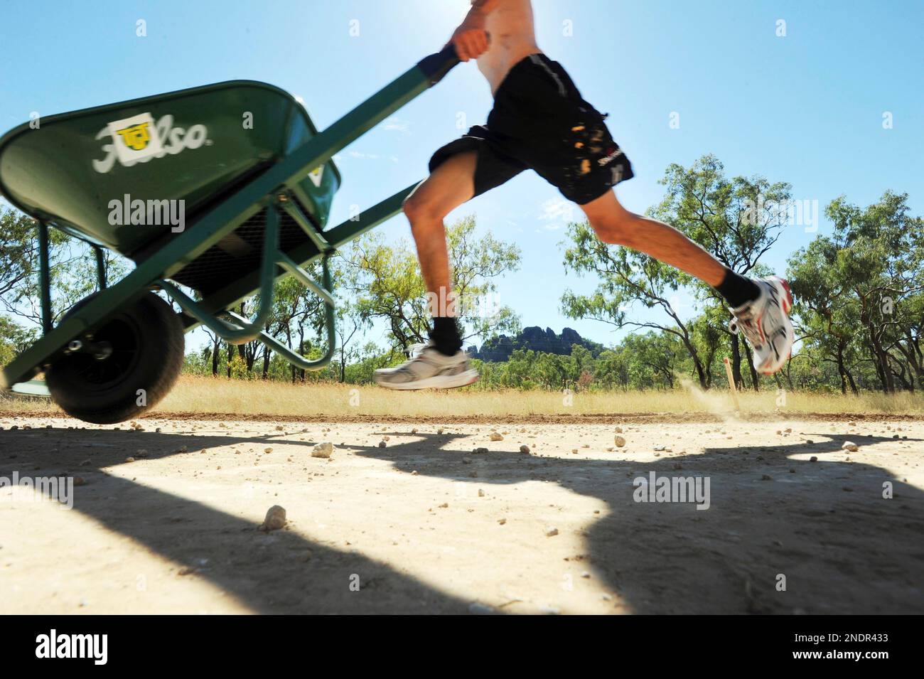 A competitor pushes a wheelbarrow through the Australian bush near ...