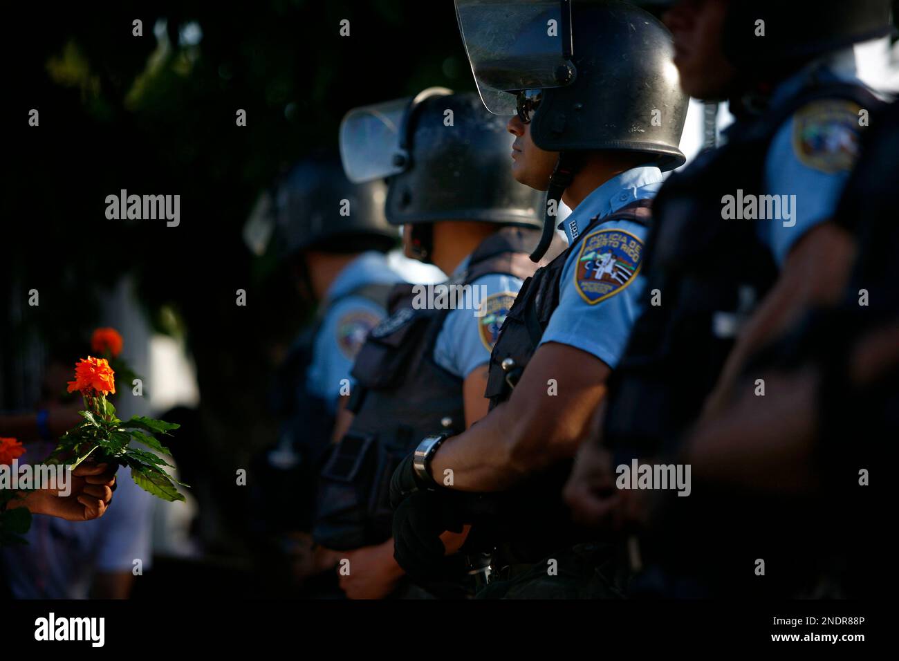 Puerto Rican riot police block protesting students, one holding out a ...