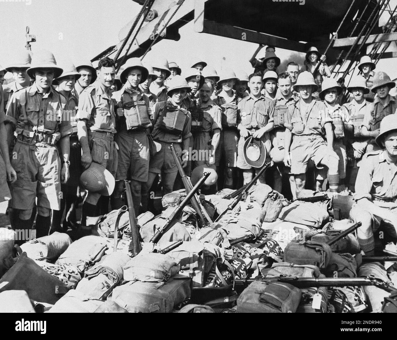 A group of British troops stand beside their rifles and knapsacks on ...