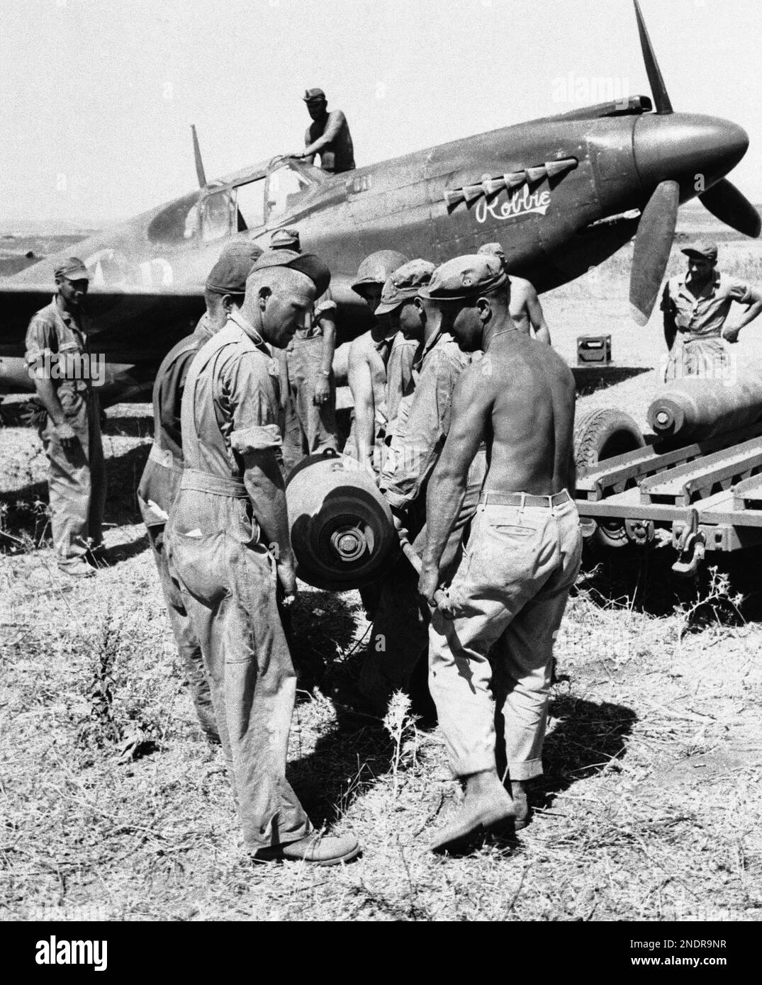 A ground crew unloads a 500-pound bomb from a bomb carrying truck for ...
