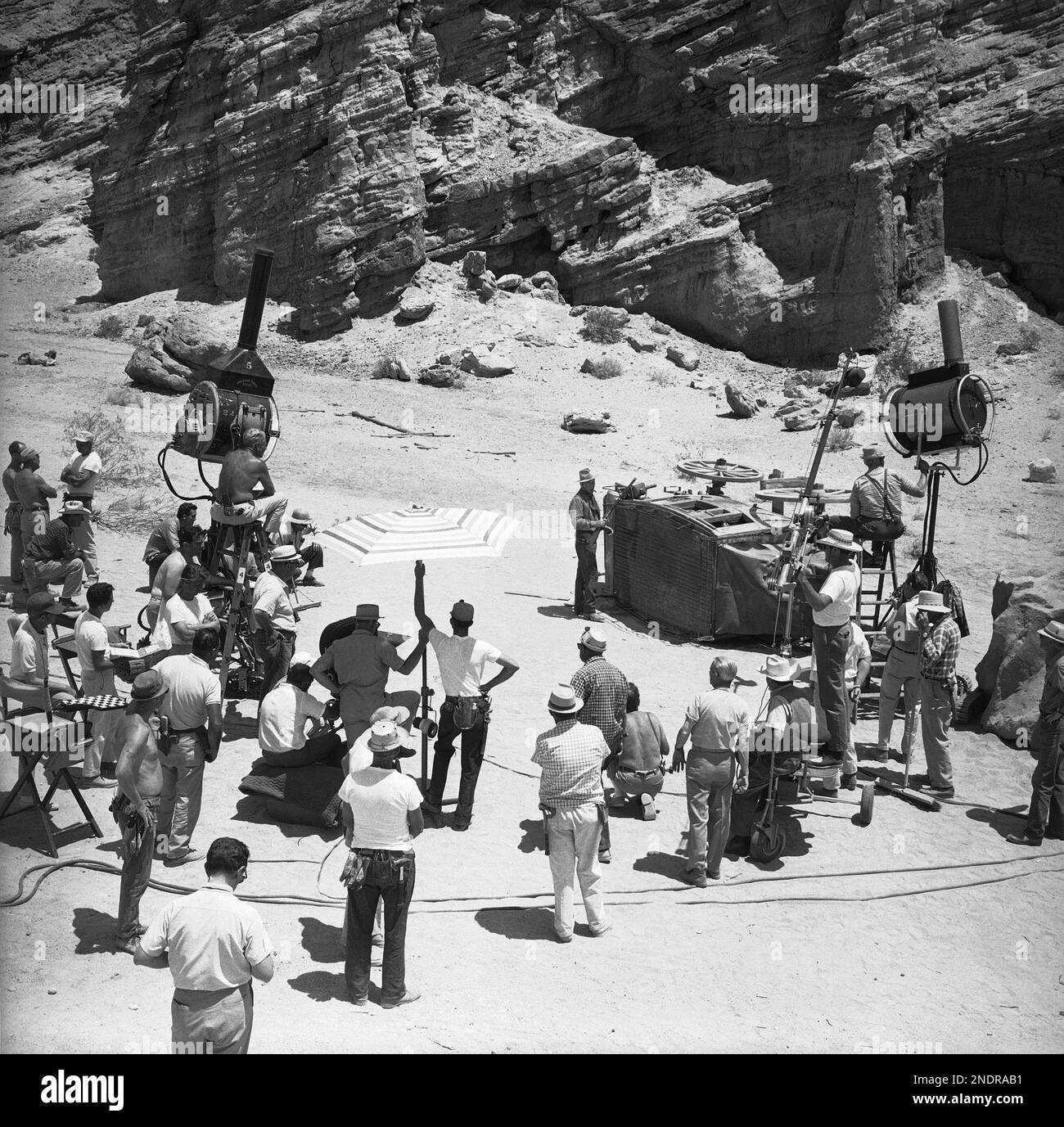 Rifle in hand, Frank Sinatra stands beside an overturned stage coach as ...