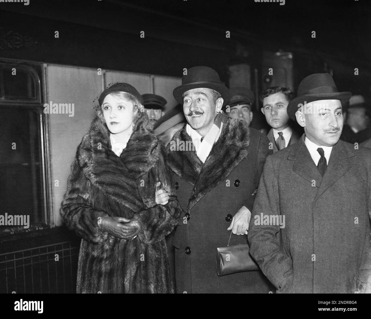 American actor Adolphe Menjou, center holding bag, with wife actress ...