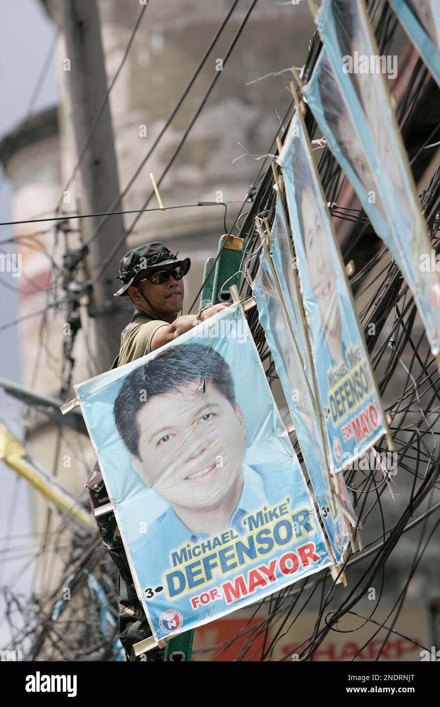 A Filipino trooper takes off campaign posters hanging on electrical ...