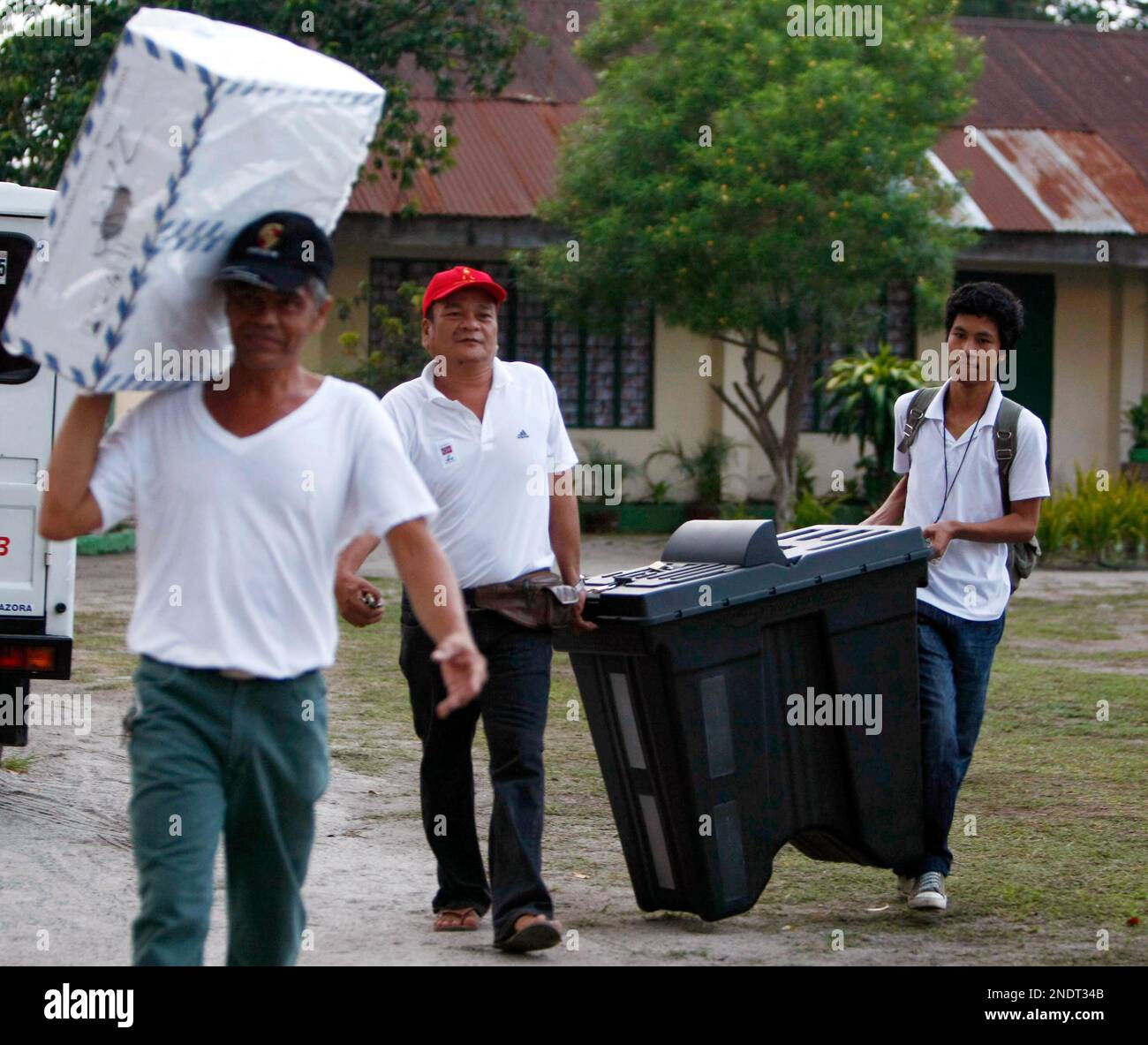 Election officials carry PCOS (Precinct Count Optical Scan) machine and ...