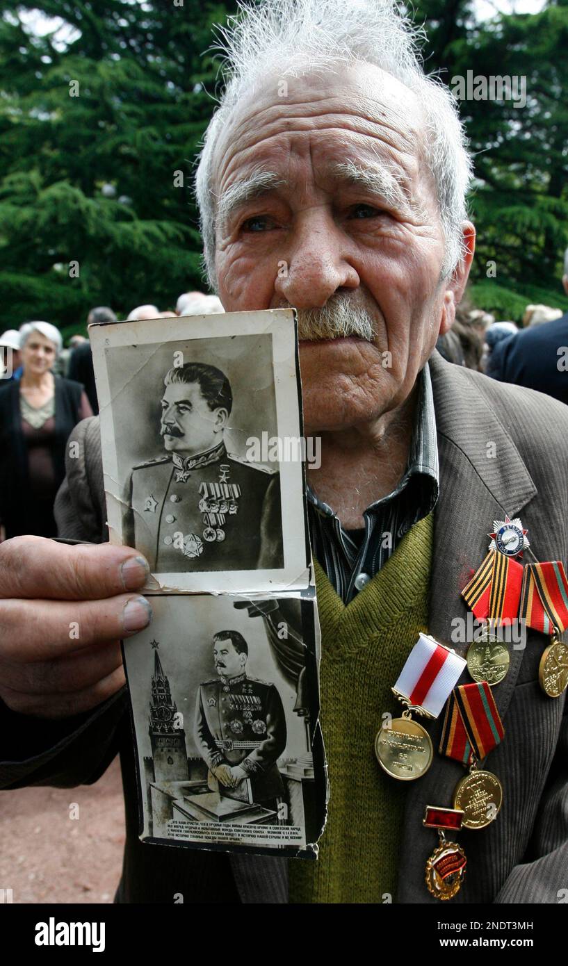 A World War II veteran holds portraits of Soviet dictator Joseph Stalin ...