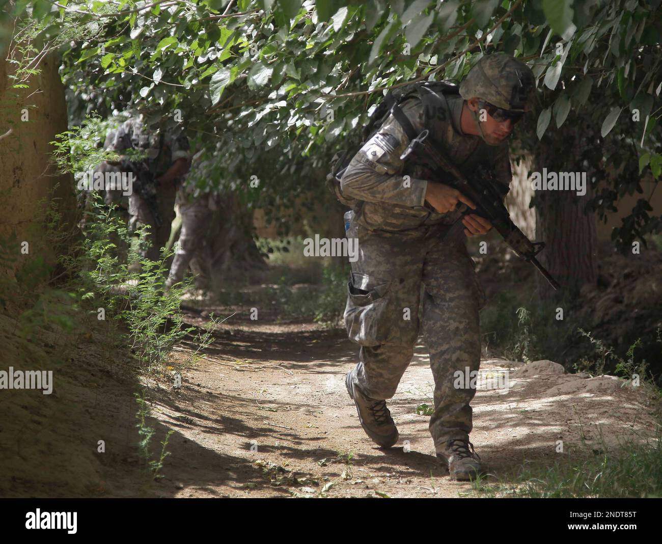U.S. Army Pfc. James Lifsey ducks as he walks under tree cover while on ...