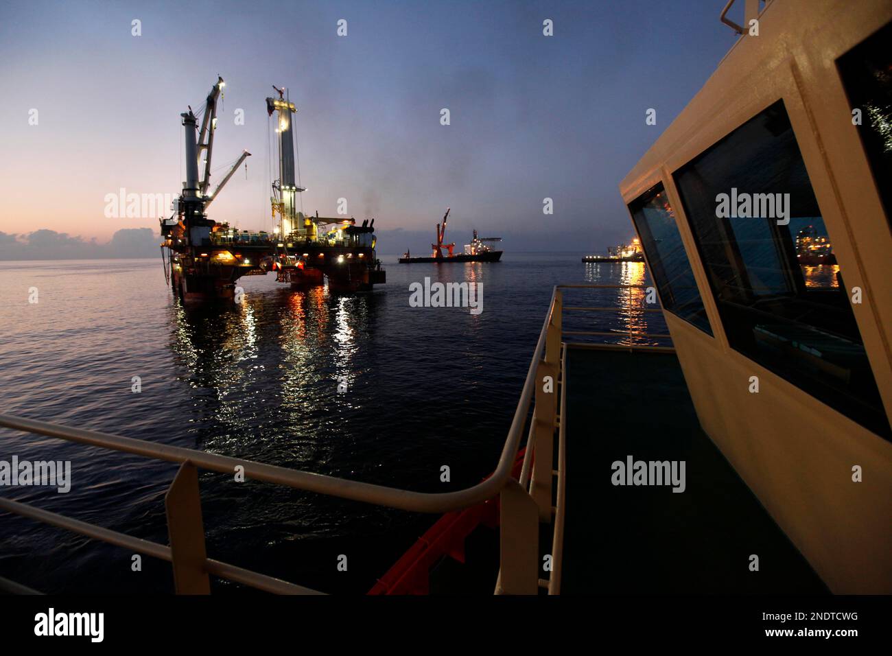 The Joe Griffin, foreground, carrying the containment vessel, positions ...