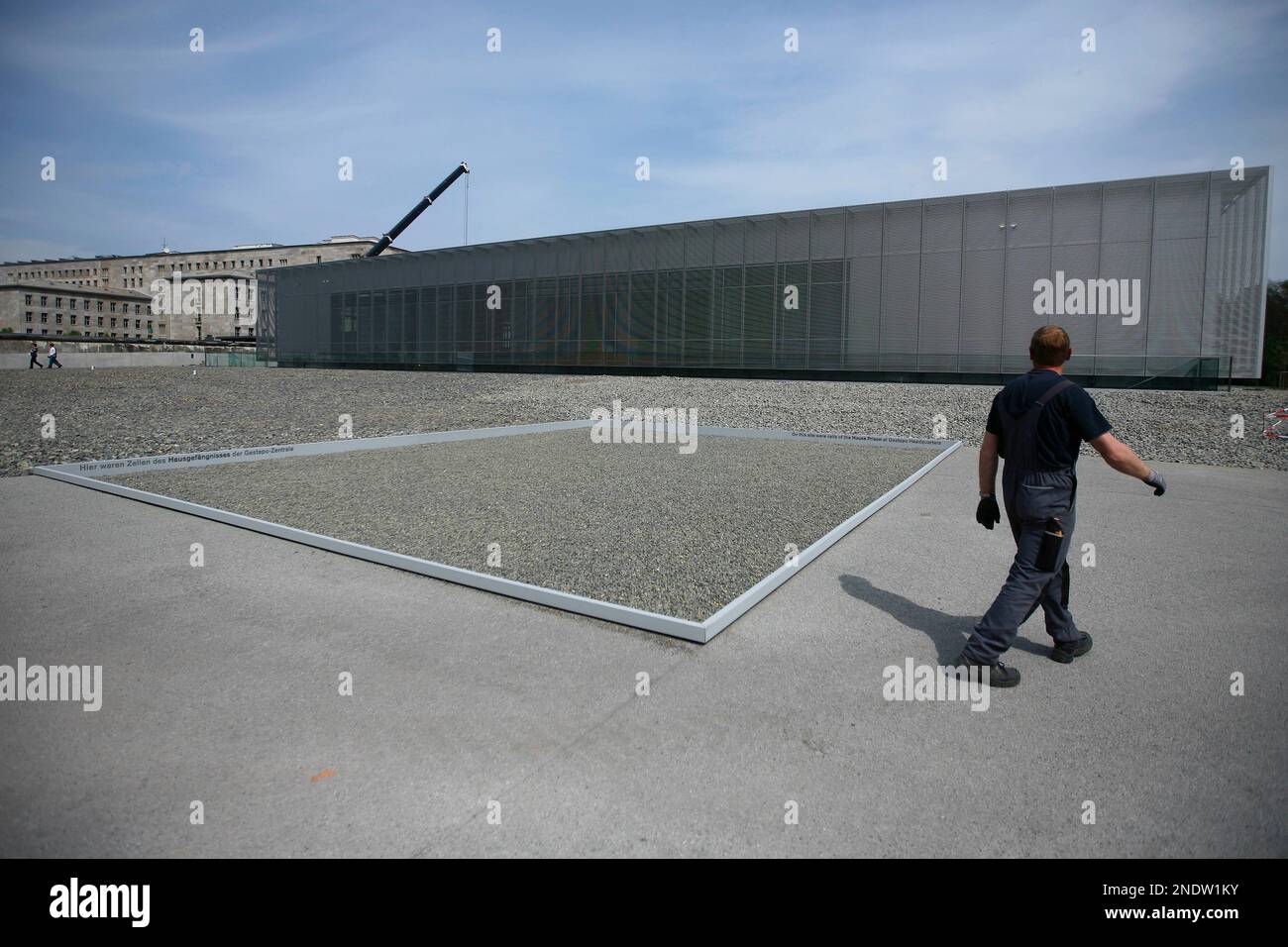 A worker passes a monument on the ground marking cellars of the Gestapo ...
