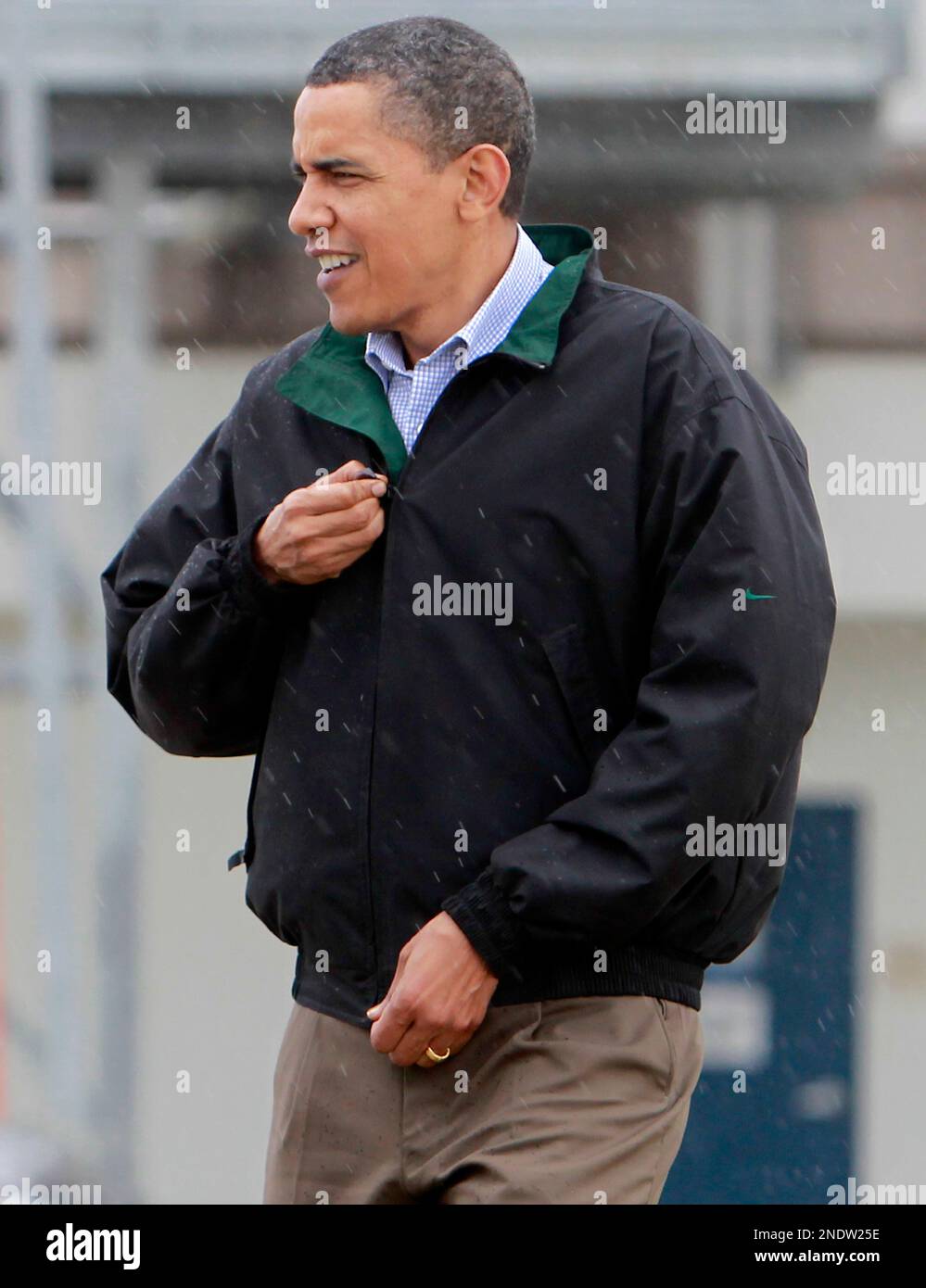 President Barack Obama zips up his jacket as it begins to rain in ...