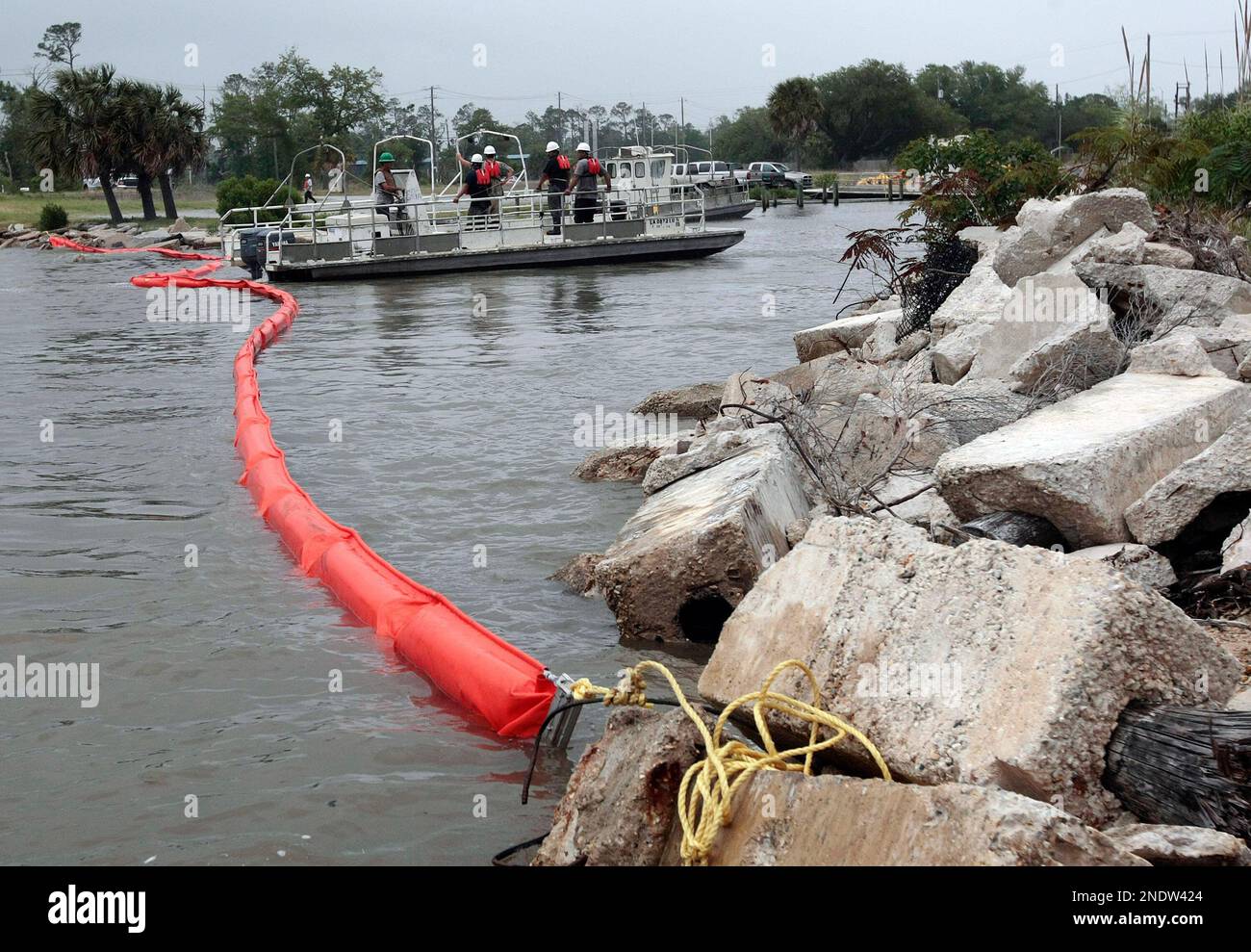 Workers maneuver their boat around oil retention booms in Bay St. Louis ...