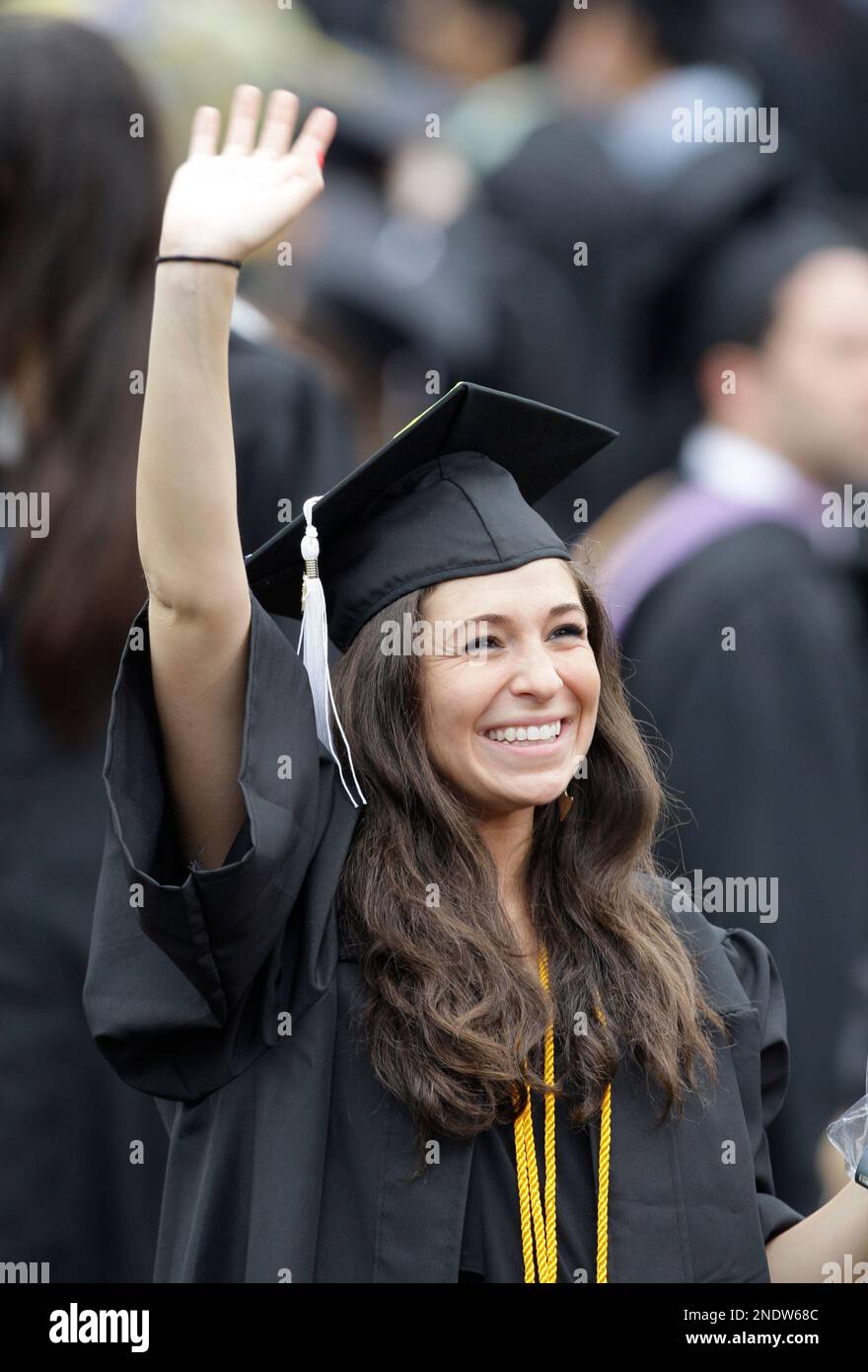 A graduate waves at the University of Michigan graduation ceremony at ...