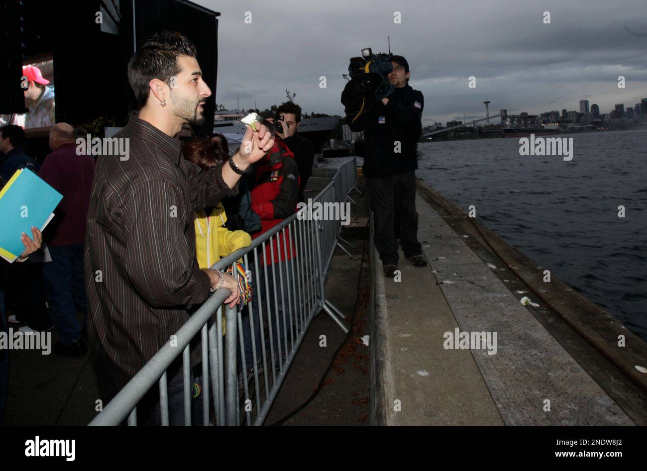 Josh Harris prepares to throw a white carnation into Elliott Bay in ...