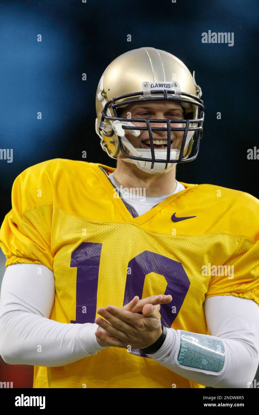 Washington quarterback Jake Locker smiles as he warms his hands between ...