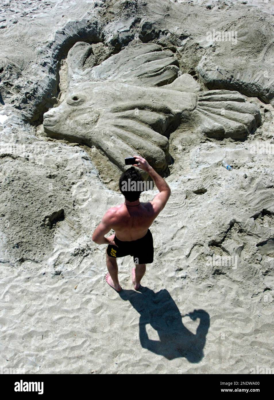 John Merle, 22, uses his cell phone to take a photo of his sand relief ...