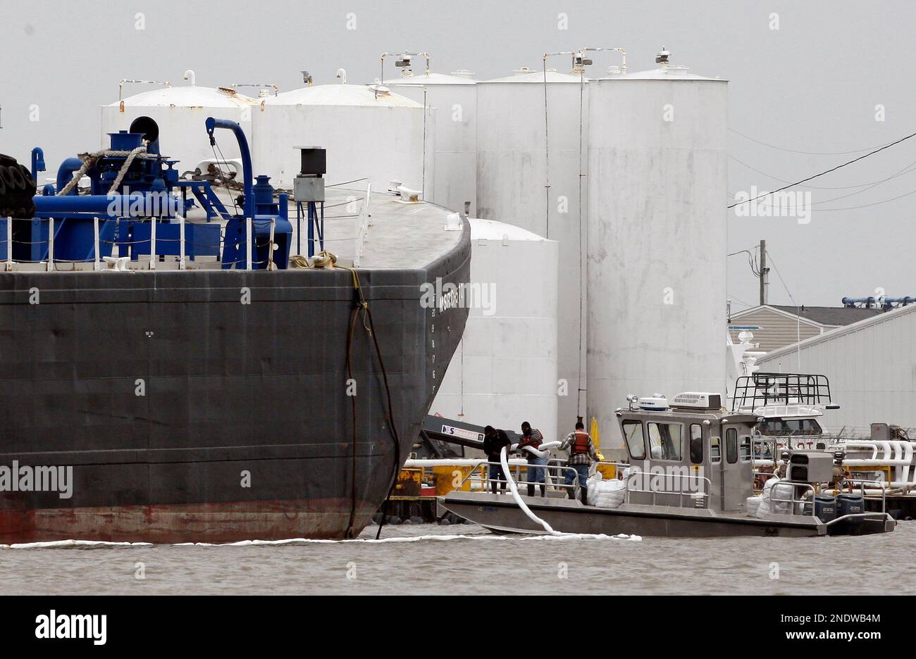 Workers lay oil booms around a barge operated by the Marine Spill ...