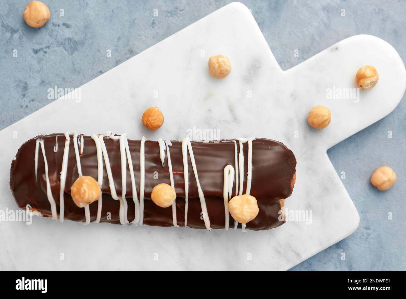 Board with delicious chocolate eclair and hazelnuts on grey table Stock ...