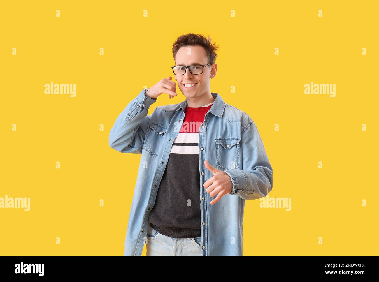Cool young man showing "call me" gesture on yellow background Stock ...