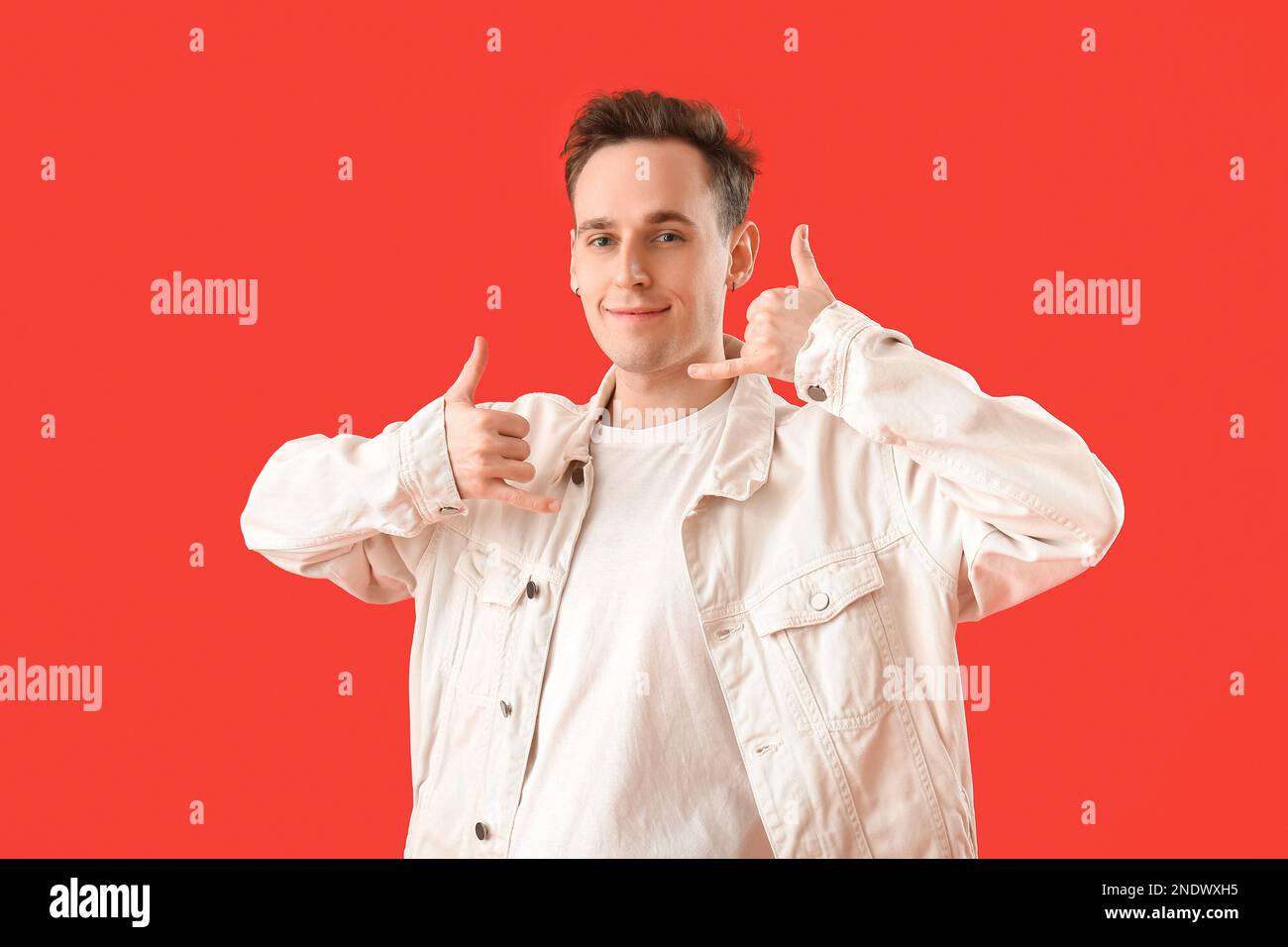 Cool young man showing "call me" gesture on red background Stock Photo ...