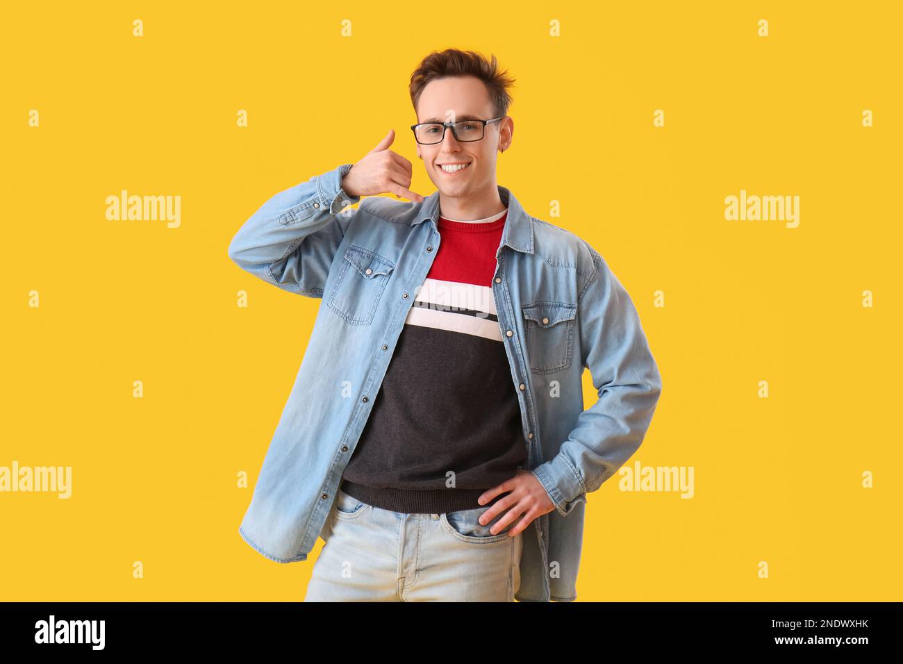 Cool young man showing "call me" gesture on yellow background Stock ...