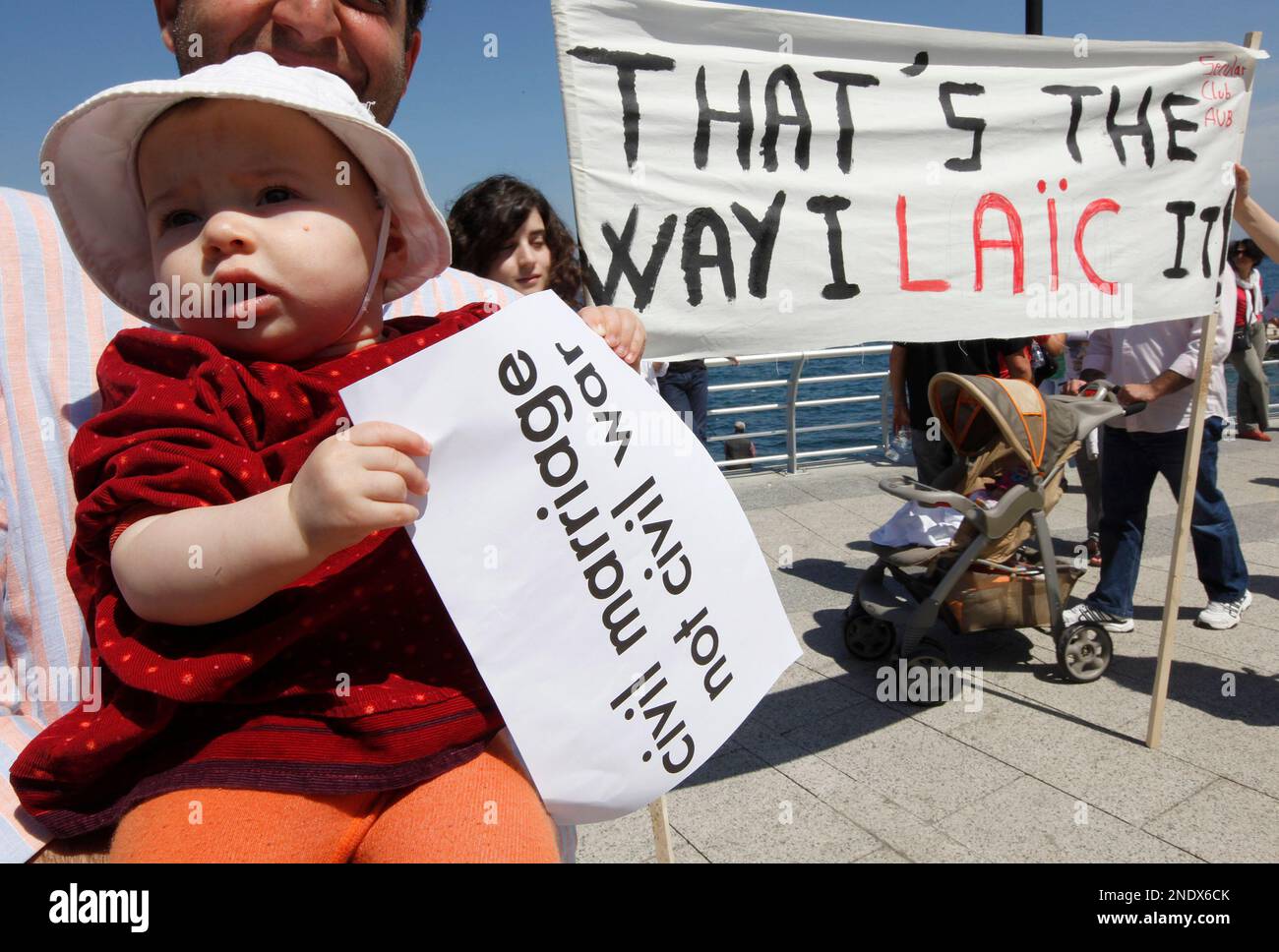 A Lebanese secular activist, holds his child as they participate in a ...
