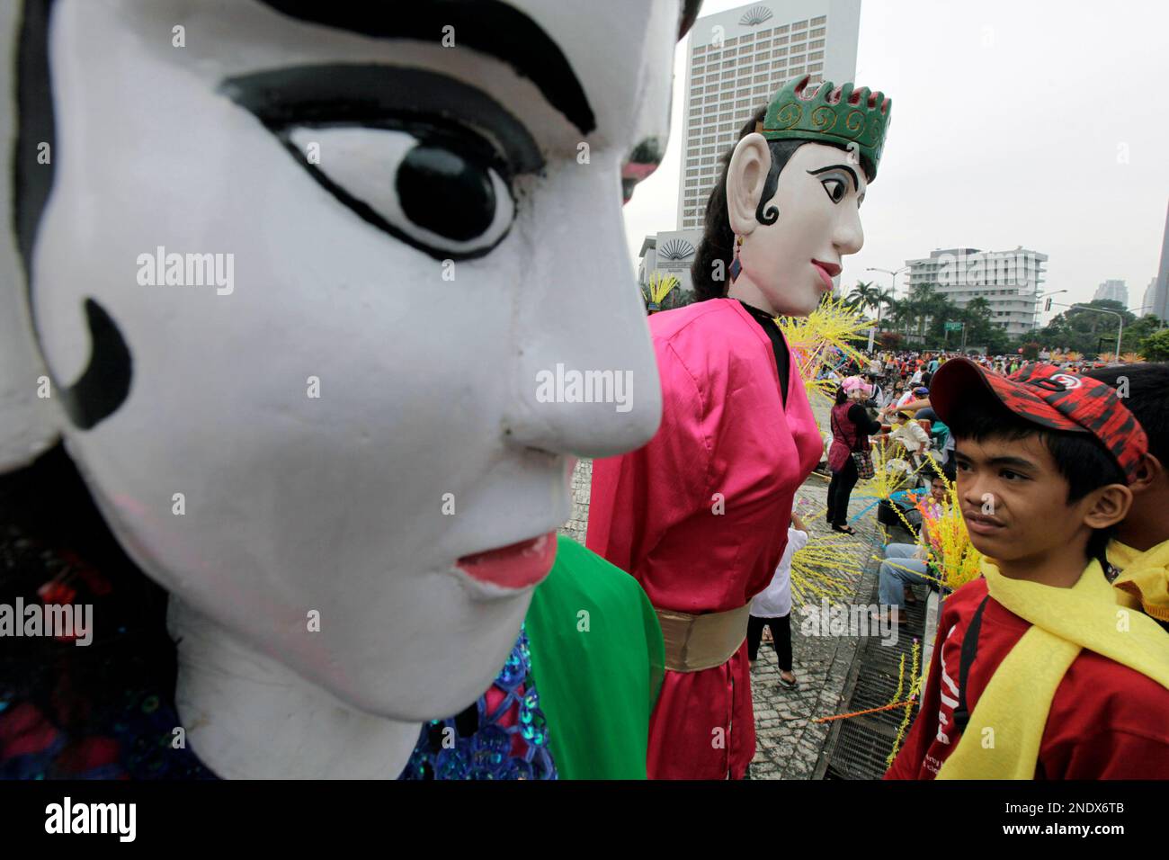 An Indonesian youth stands next to traditional giant puppets called "ondel-ondel" during a ...