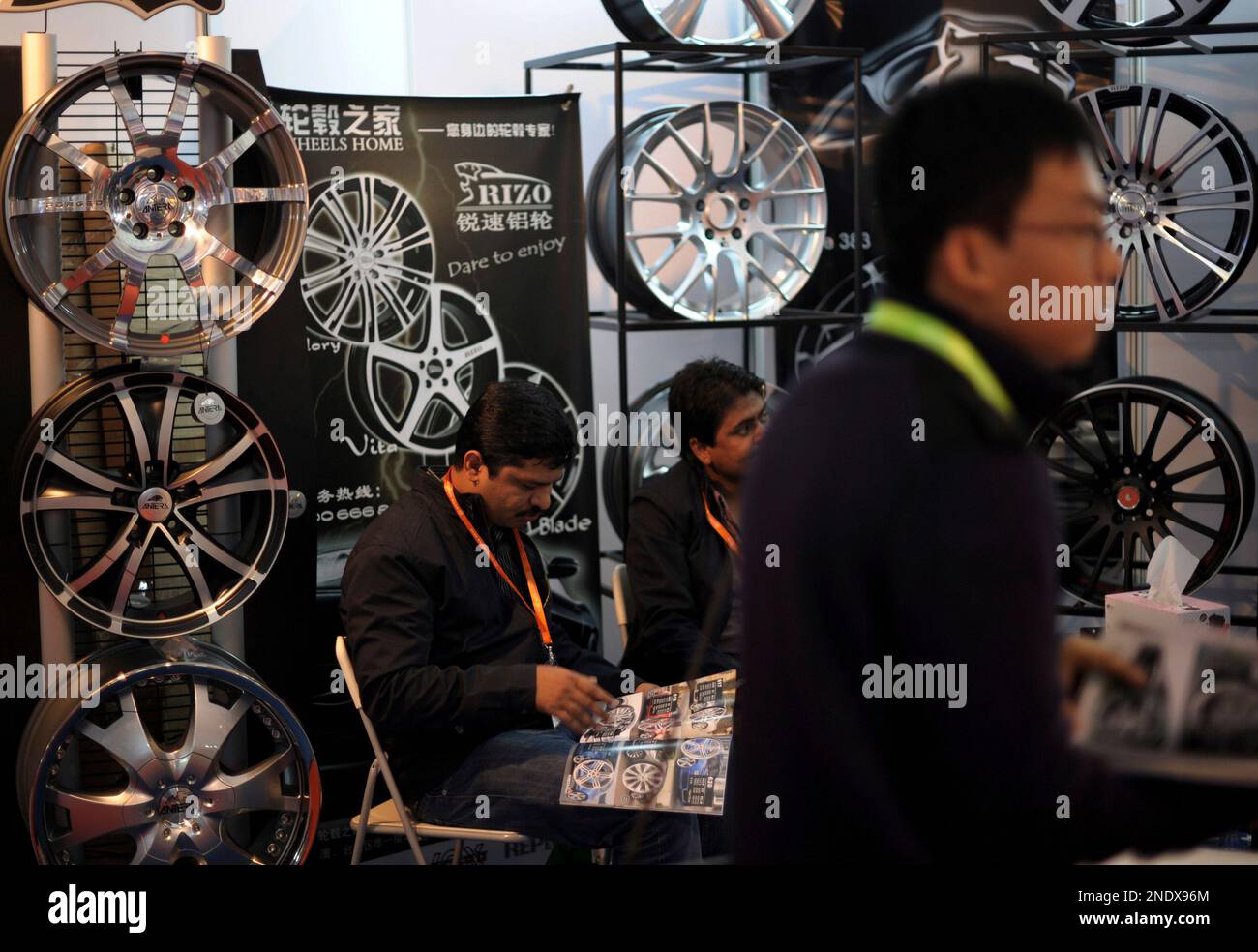 A foreign visitor browses a catalog at a booth displaying sport rims at ...